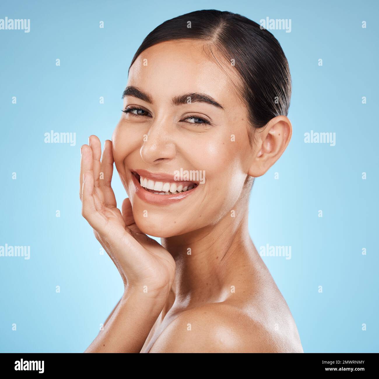 Portrait, smile and skincare with a model woman in studio on a blue ...