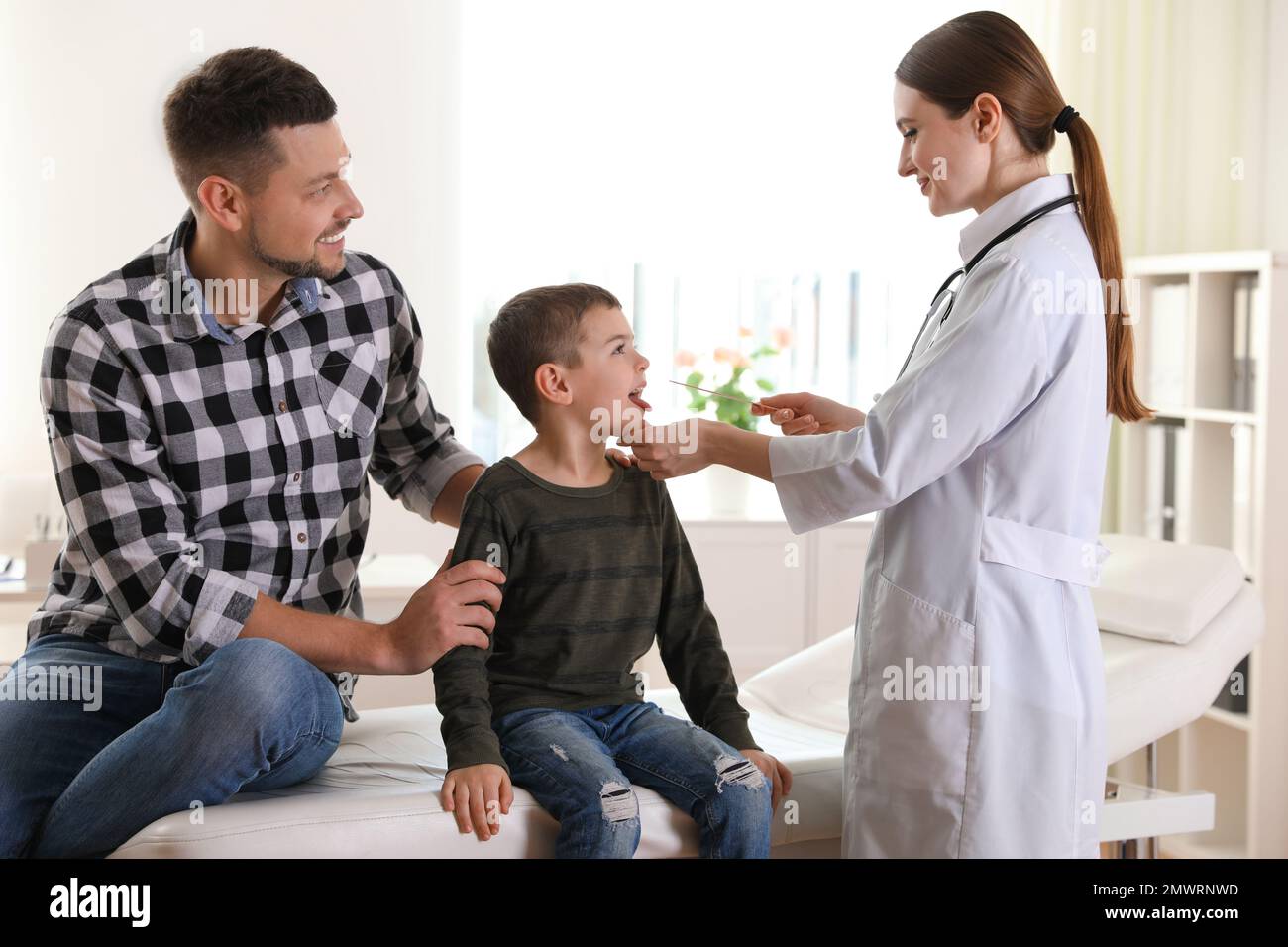 Father and son visiting pediatrician. Doctor examining little patient's ...
