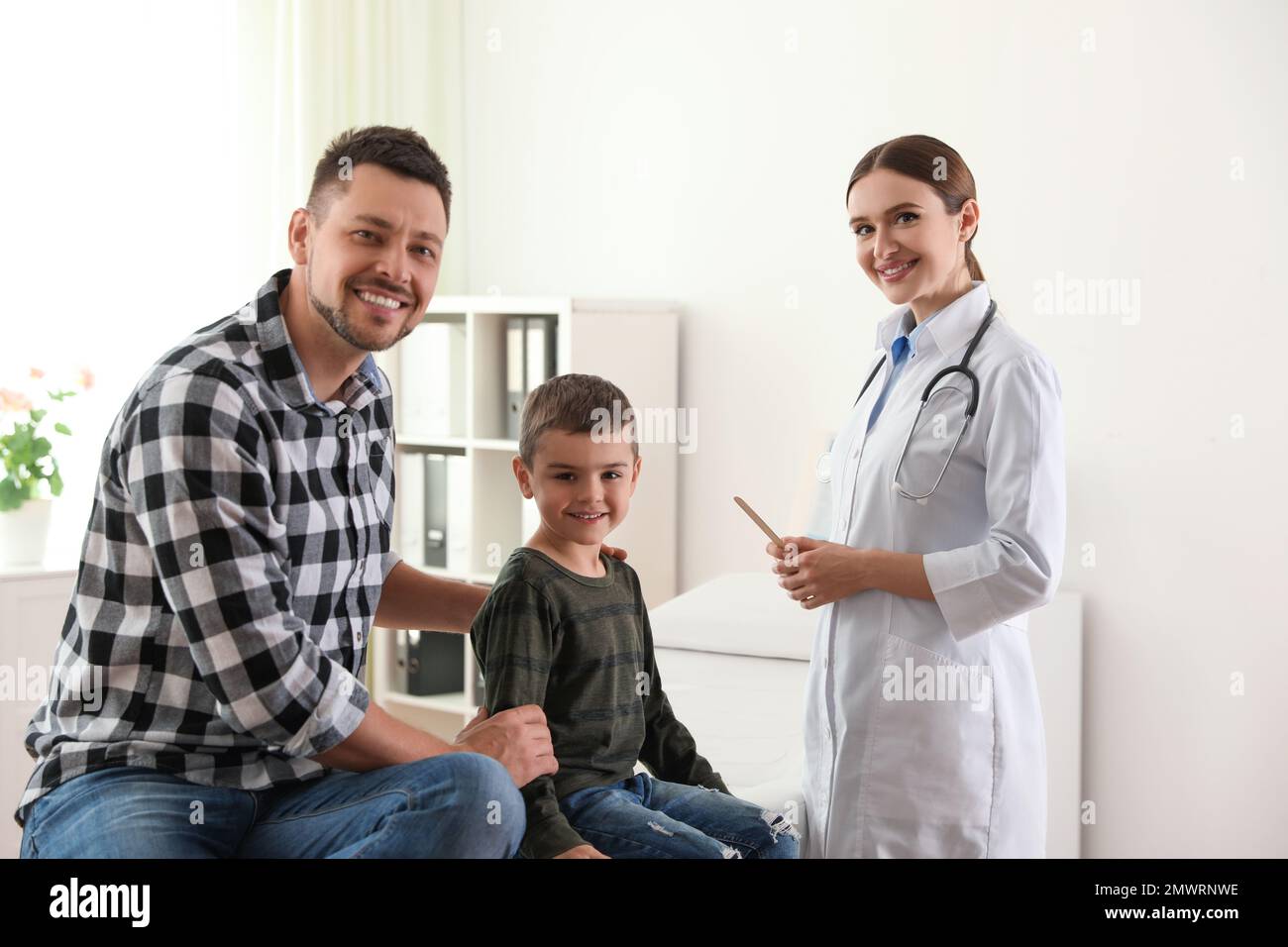 Father and son visiting pediatrician. Doctor working with patient in ...