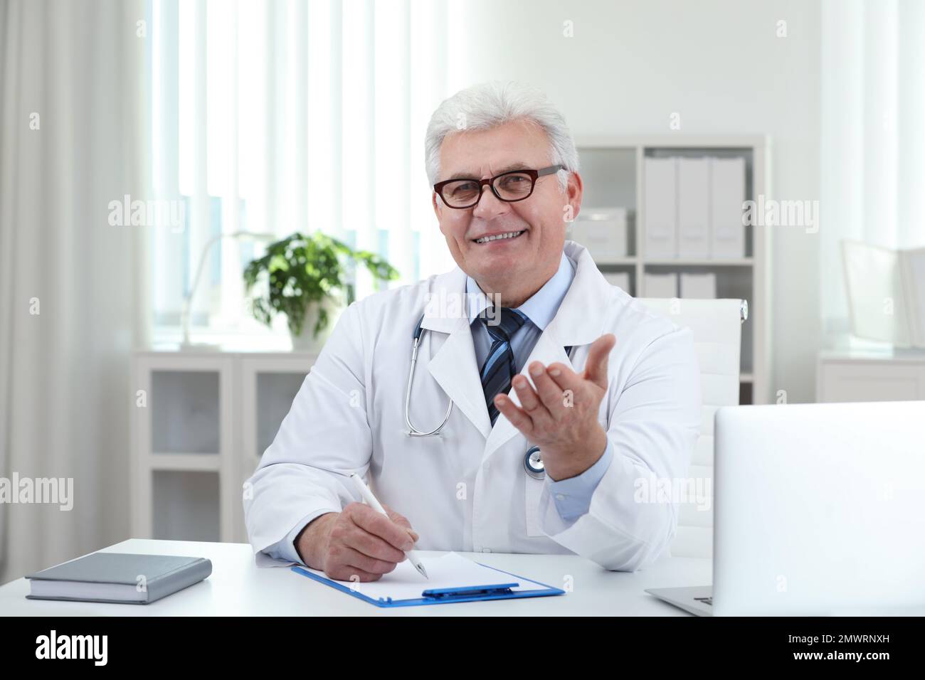 Portrait of senior doctor in white coat at workplace Stock Photo - Alamy
