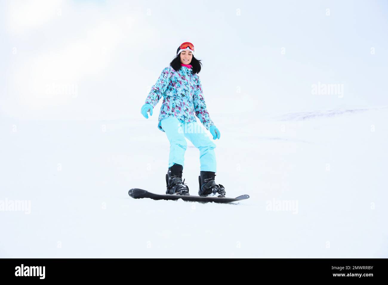 Young woman snowboarding on hill at mountain resort. Winter vacation ...