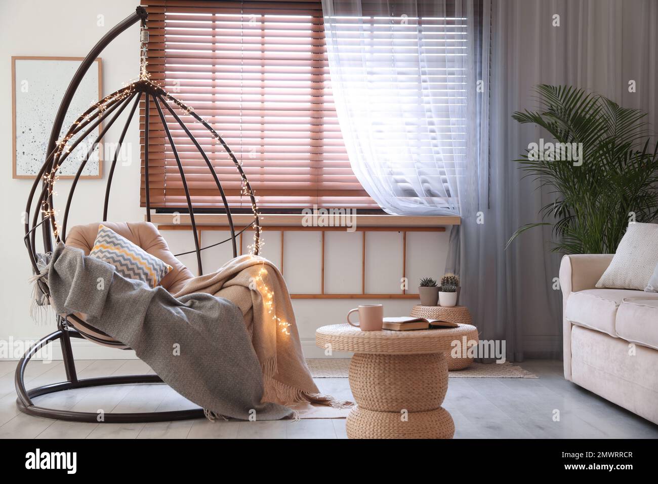 Cozy hanging chair with fairy lights in modern living room. Interior ...