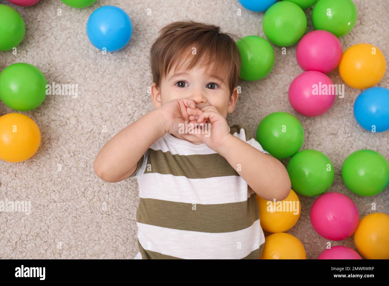 Cute little child playing with balls on floor, top view Stock Photo - Alamy