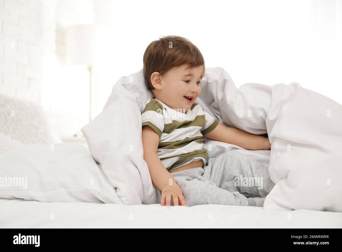 Cute little child playing under blanket in bed Stock Photo - Alamy