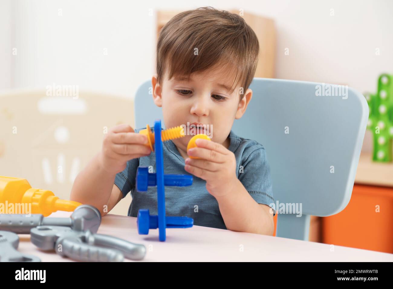 Little child playing with toy construction tools at table Stock Photo ...