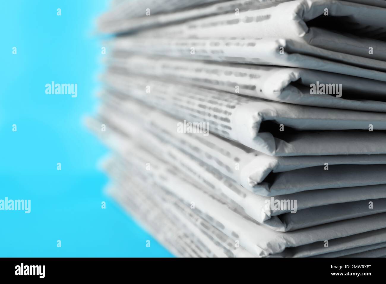 Stack of newspapers on light blue background, closeup. Journalist's ...