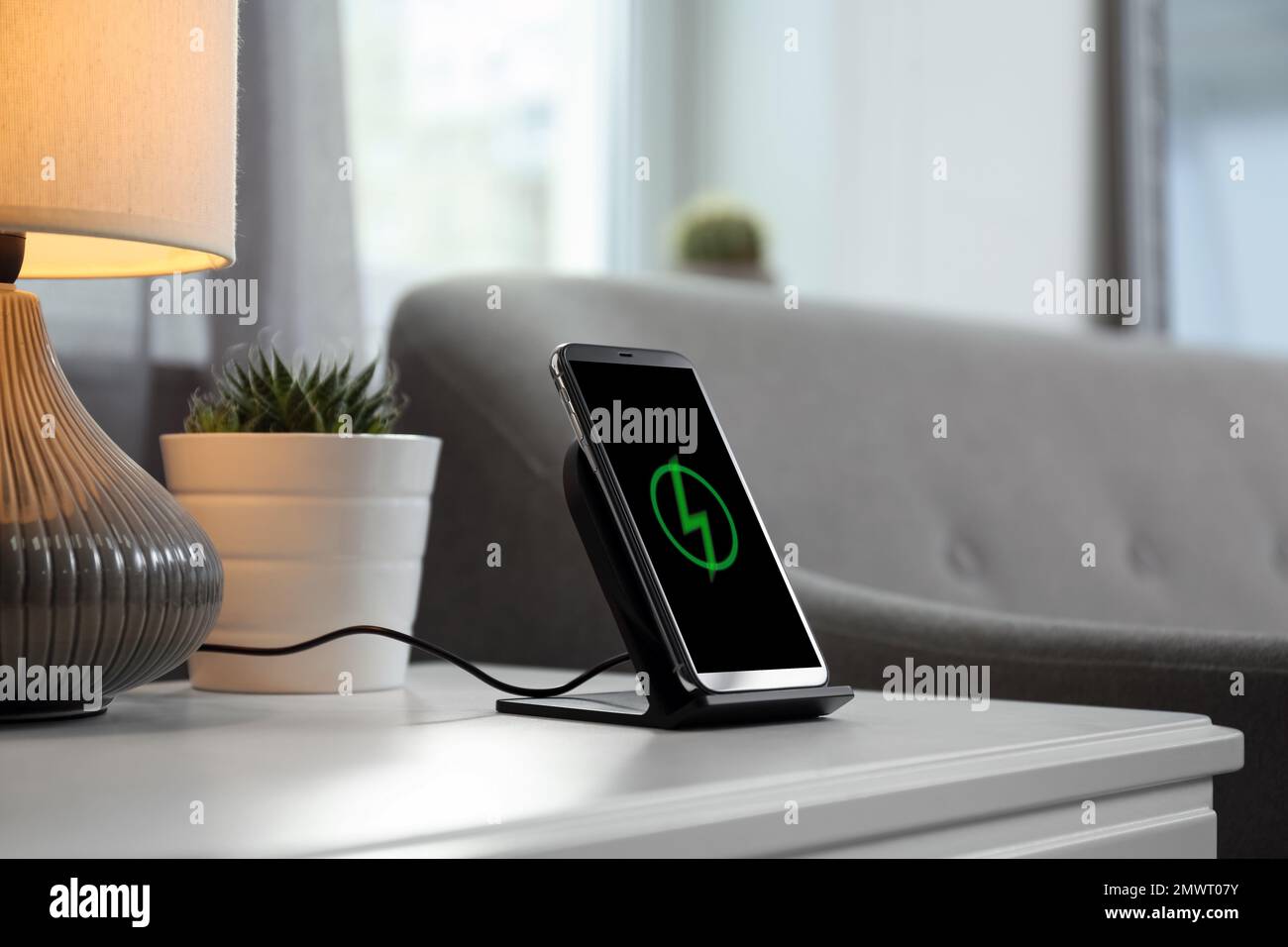 Smartphone charging on wireless pad in room Stock Photo - Alamy