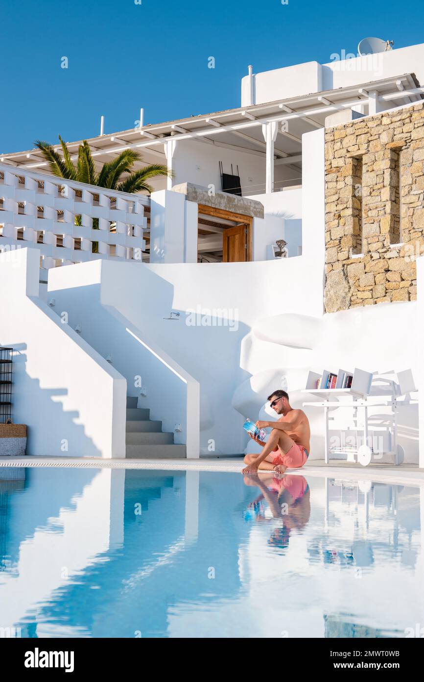 Young men read a book by the swimming pool during vacation. a young man ...