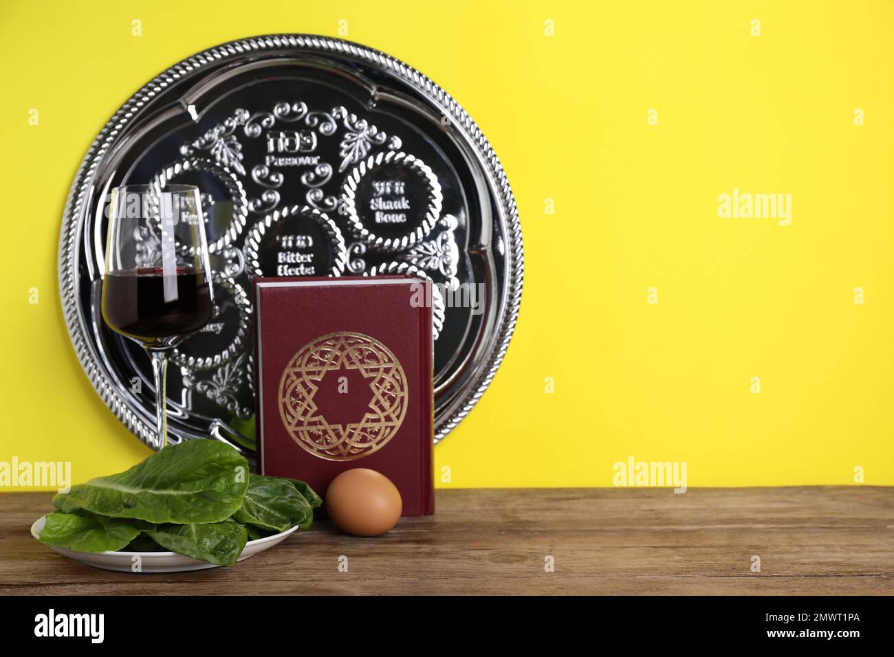 Symbolic Pesach (Passover Seder) items on wooden table against yellow ...