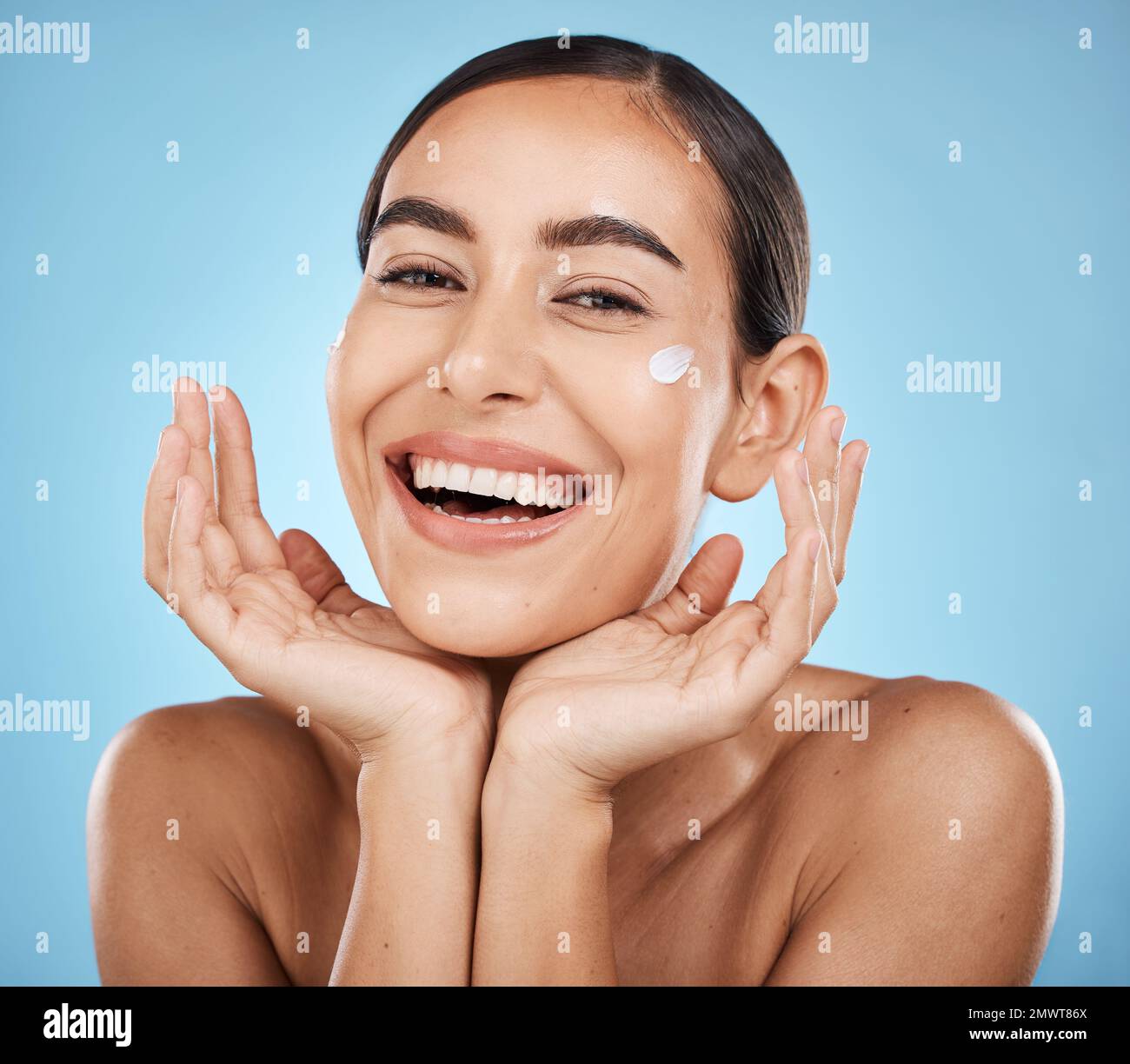 Portrait, hands and cream with a model woman in studio on a blue ...