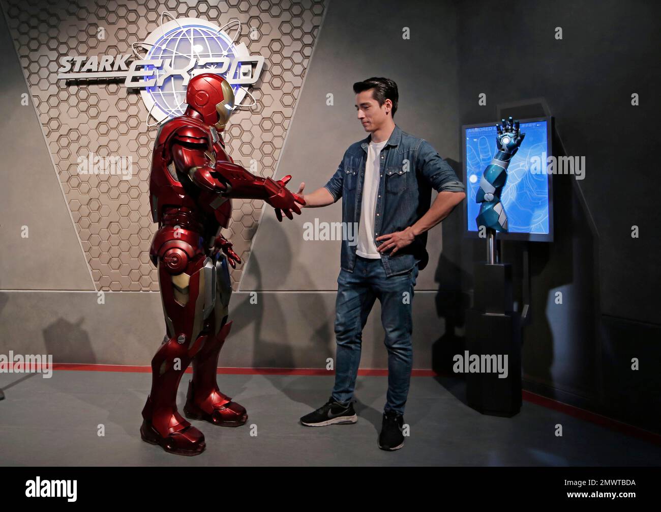 A performer dressed as Iron Man shakes hands with a man at the new ...