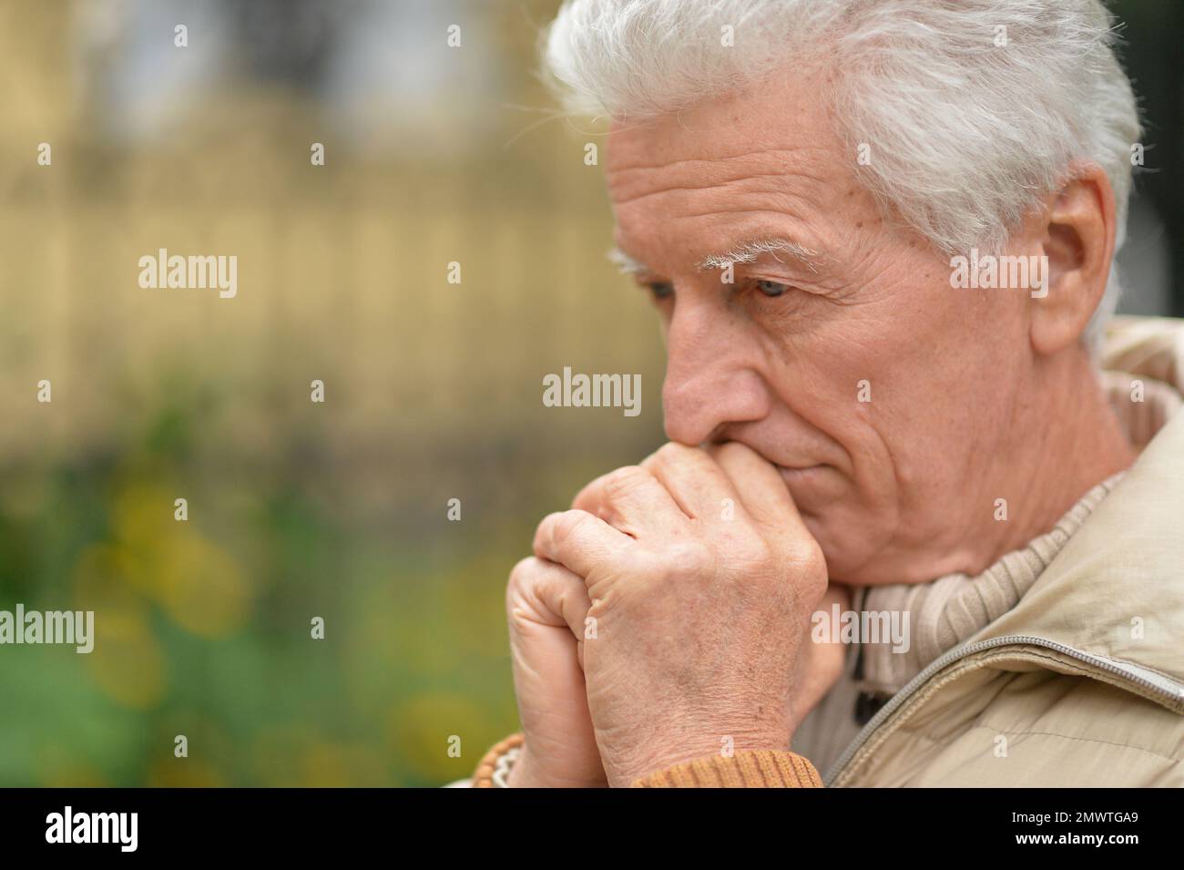 Serious old man thinking in park on green background Stock Photo - Alamy