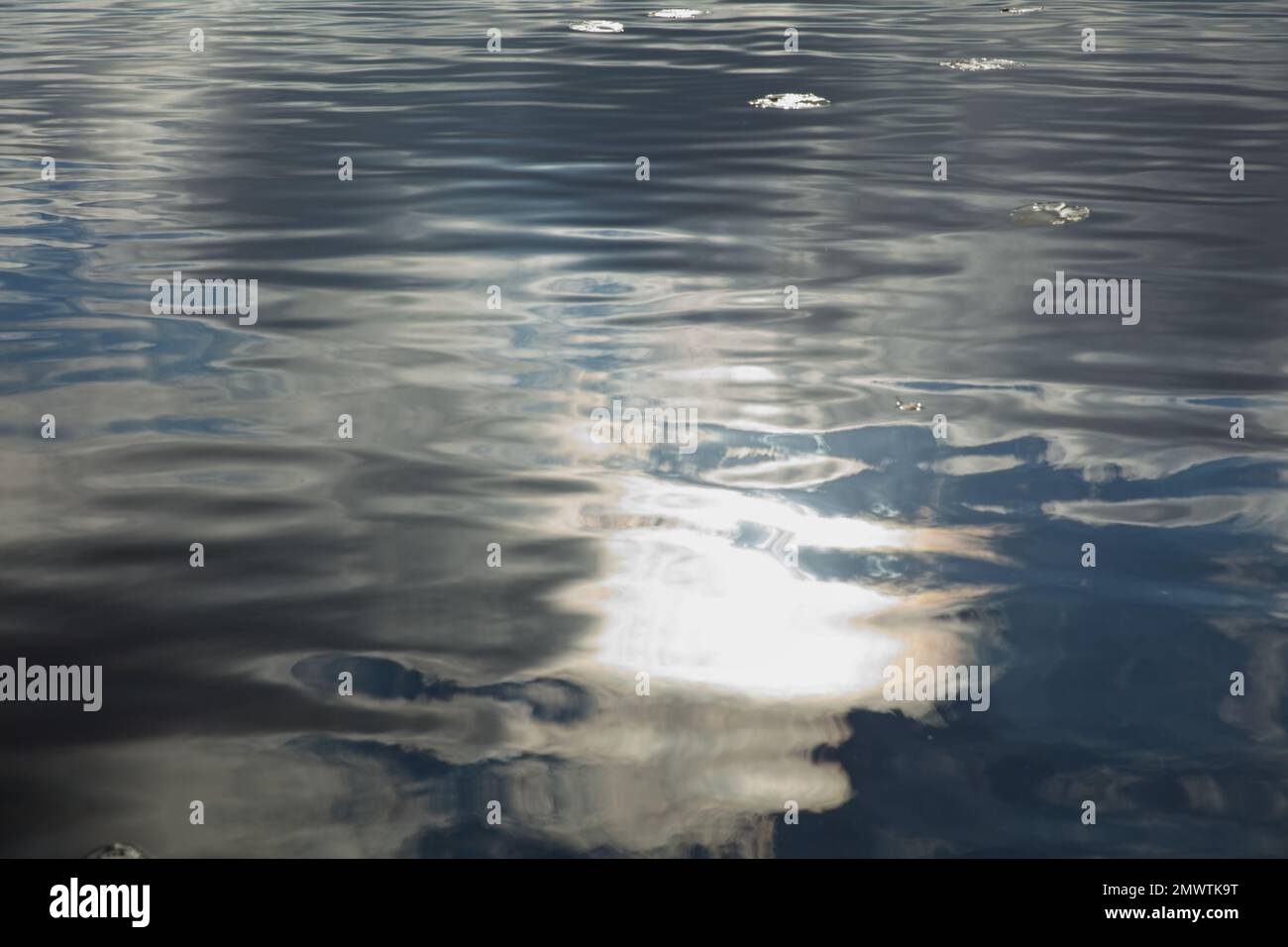 Reflections of clouds in the sky on water surface with small ripple ...
