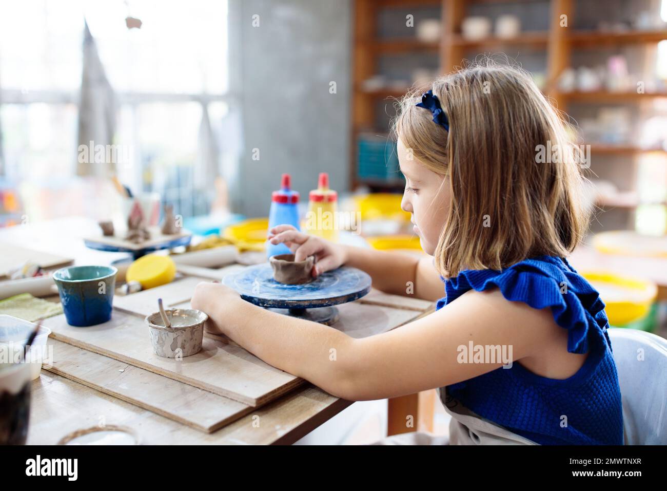 Child working on pottery wheel. Kids arts and crafts class in workshop ...