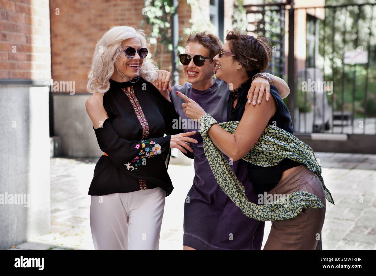 Three happy female friends laughing and cuddling outside. Lifestyle ...