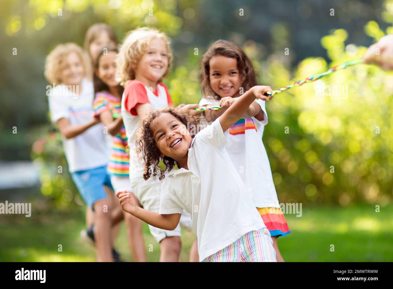 Kids play tug of war in sunny park. Summer outdoor fun activity. Group ...