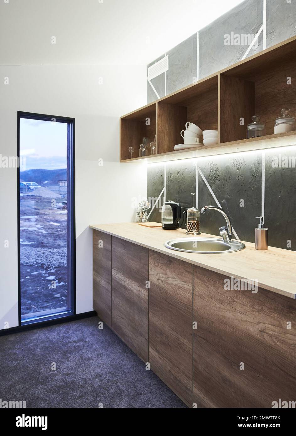 Modern kitchen with white walls and glass door with scenic view inside ...