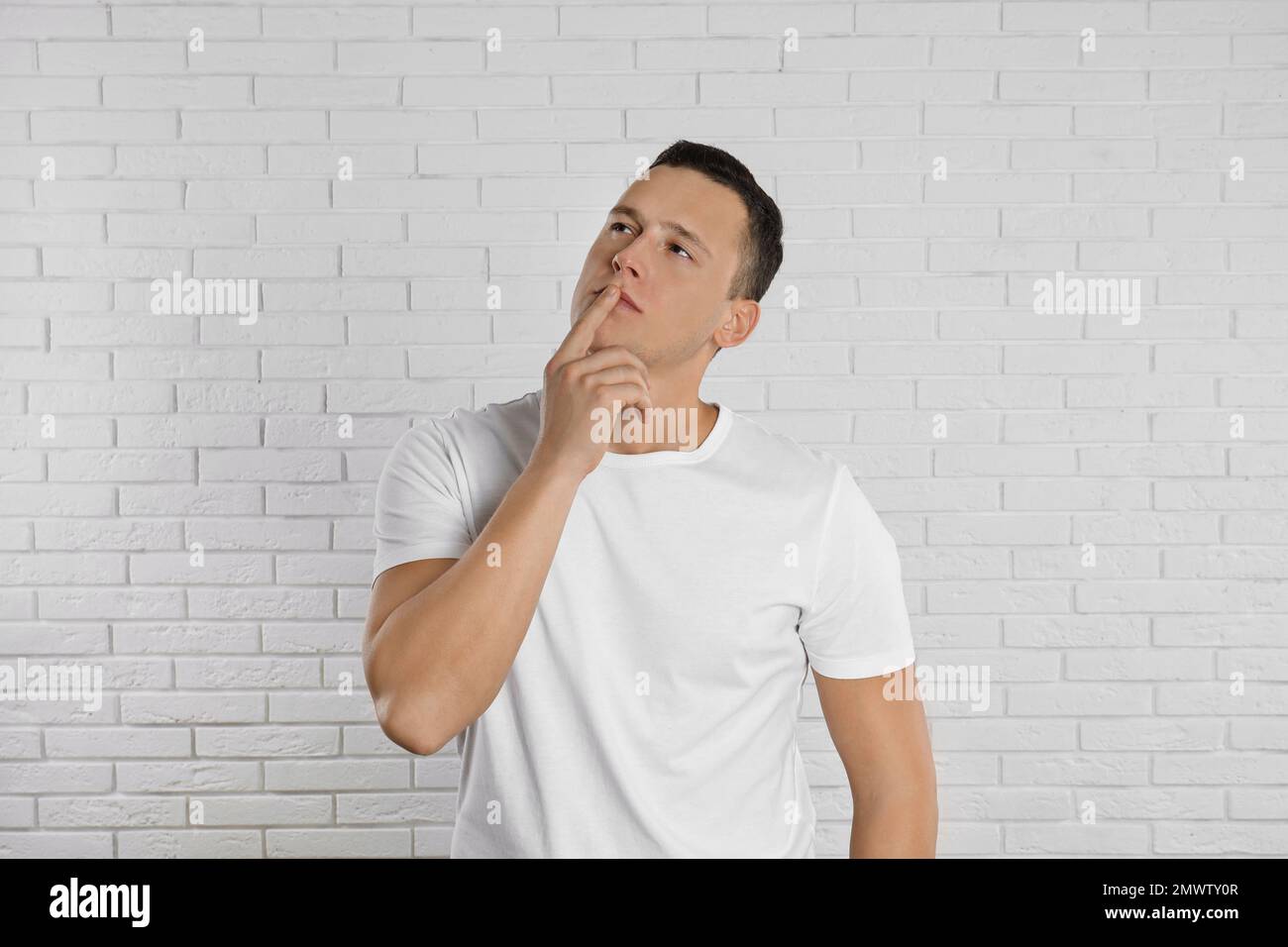 Handsome young man near white brick wall Stock Photo - Alamy