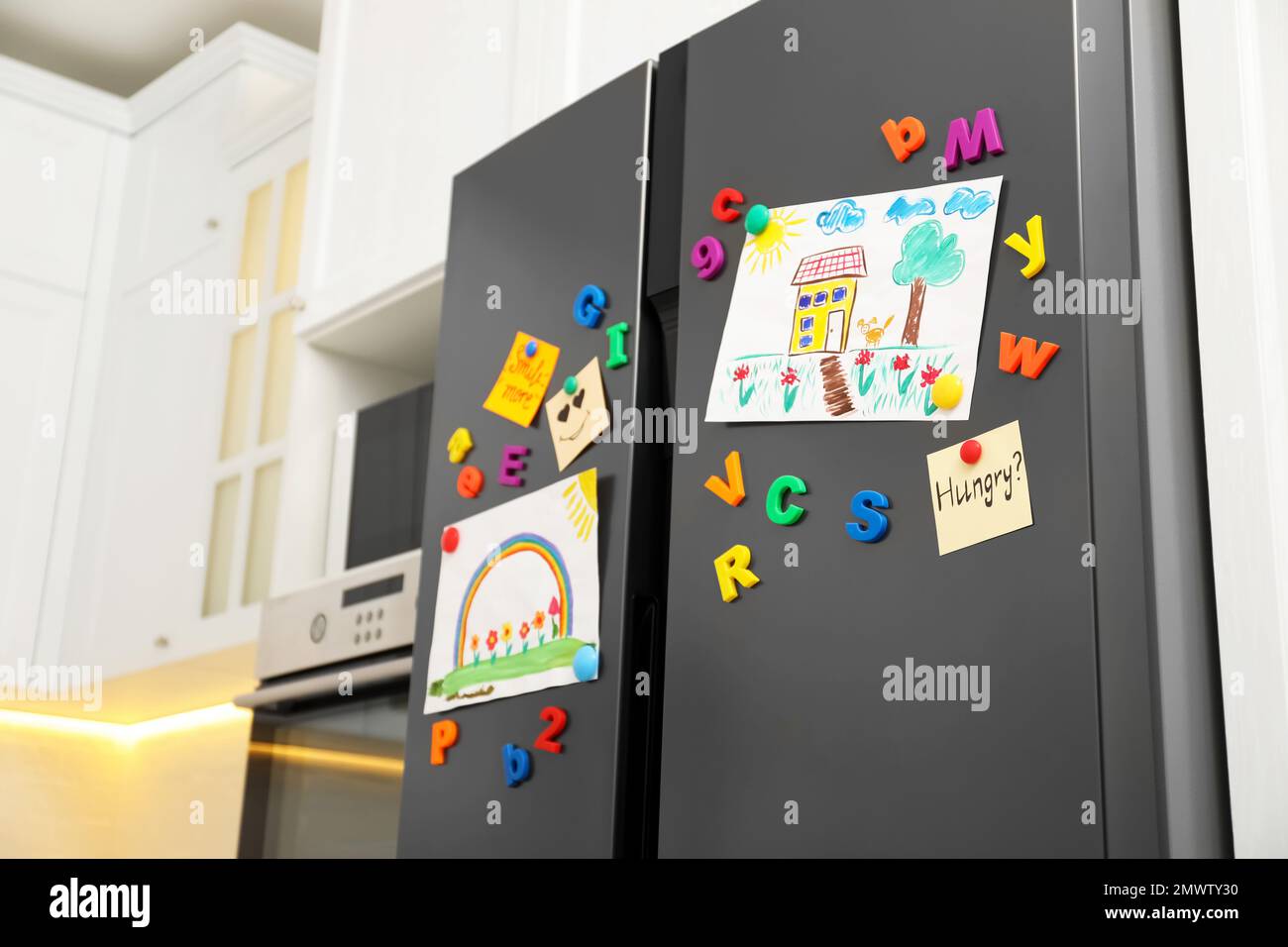 Modern refrigerator with child's drawings, notes and magnets in kitchen ...