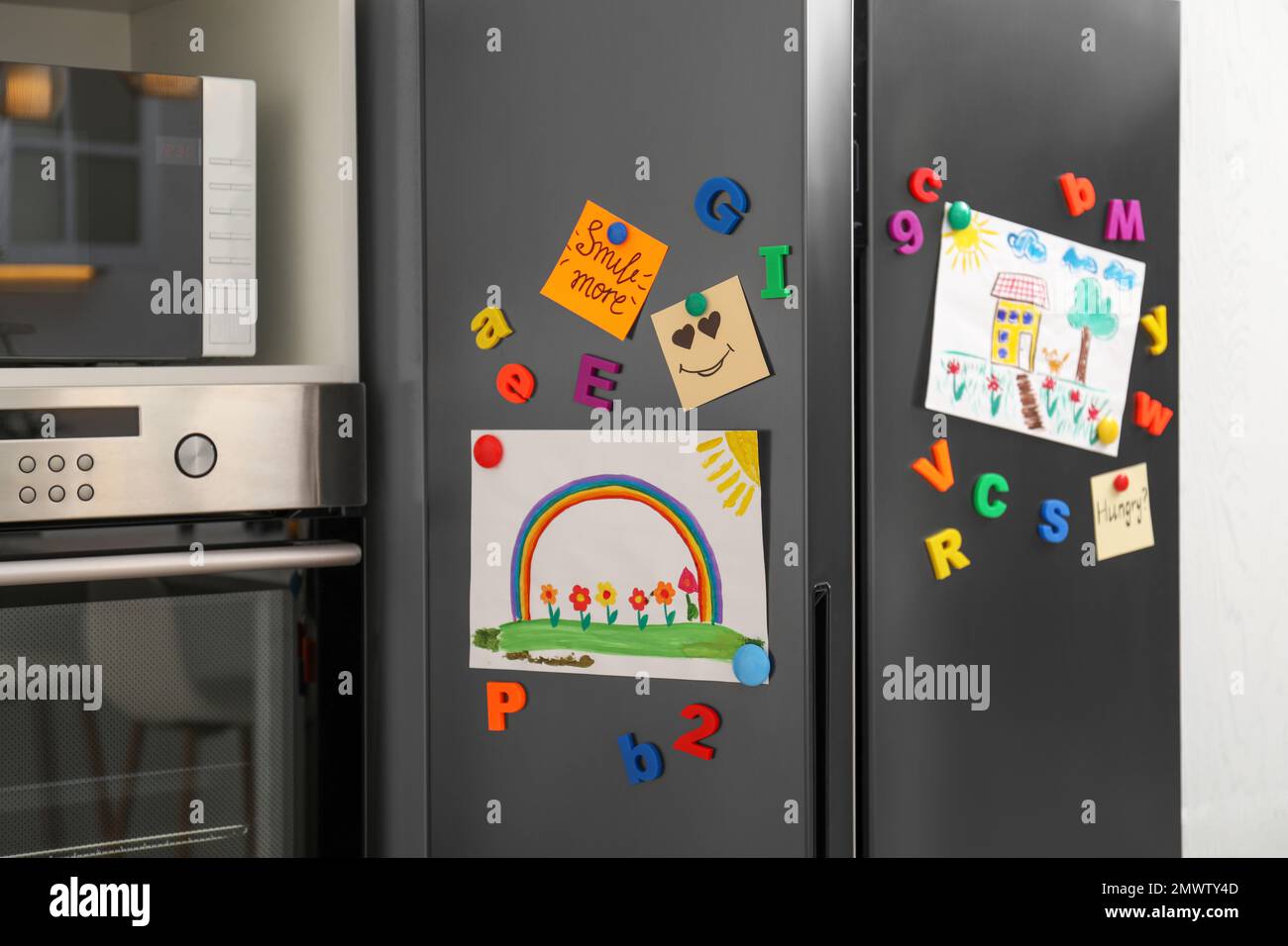 Modern refrigerator with child's drawings, notes and magnets in kitchen ...