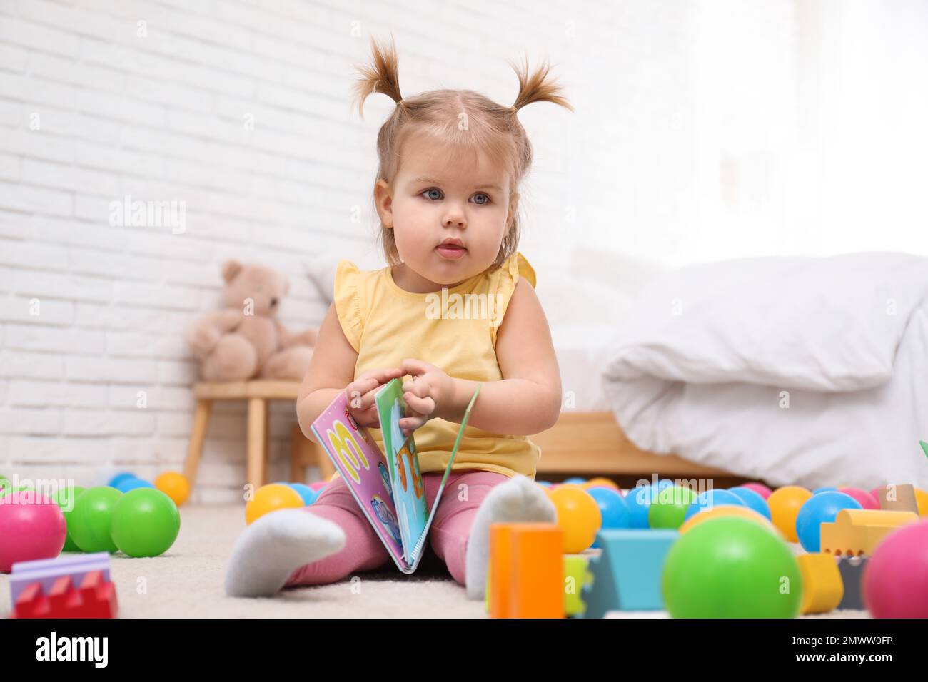 Cute little child with book playing on floor Stock Photo - Alamy