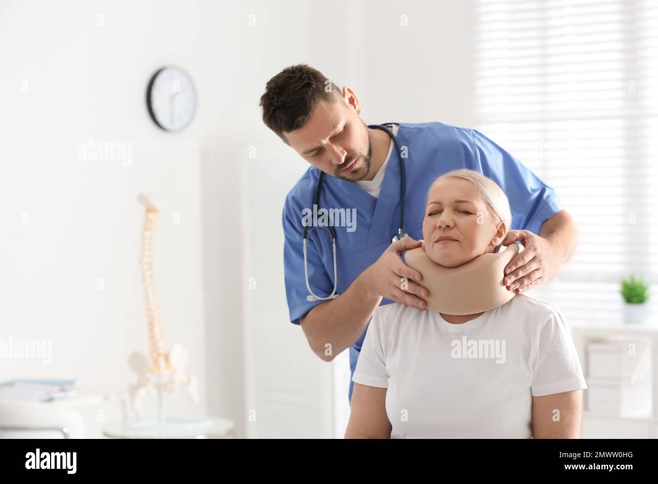 Orthopedist applying cervical collar onto patient's neck in clinic ...