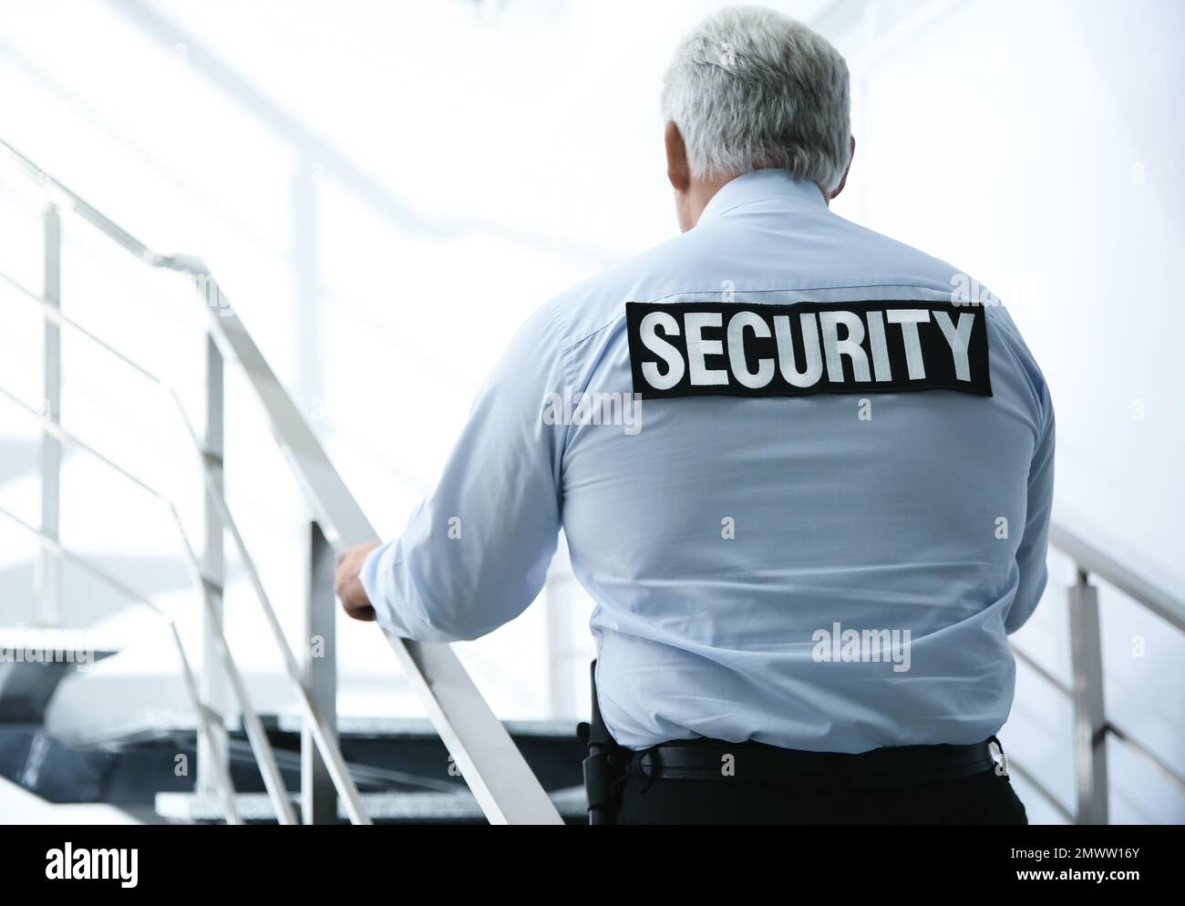 Professional security guard on stairs indoors, back view Stock Photo ...