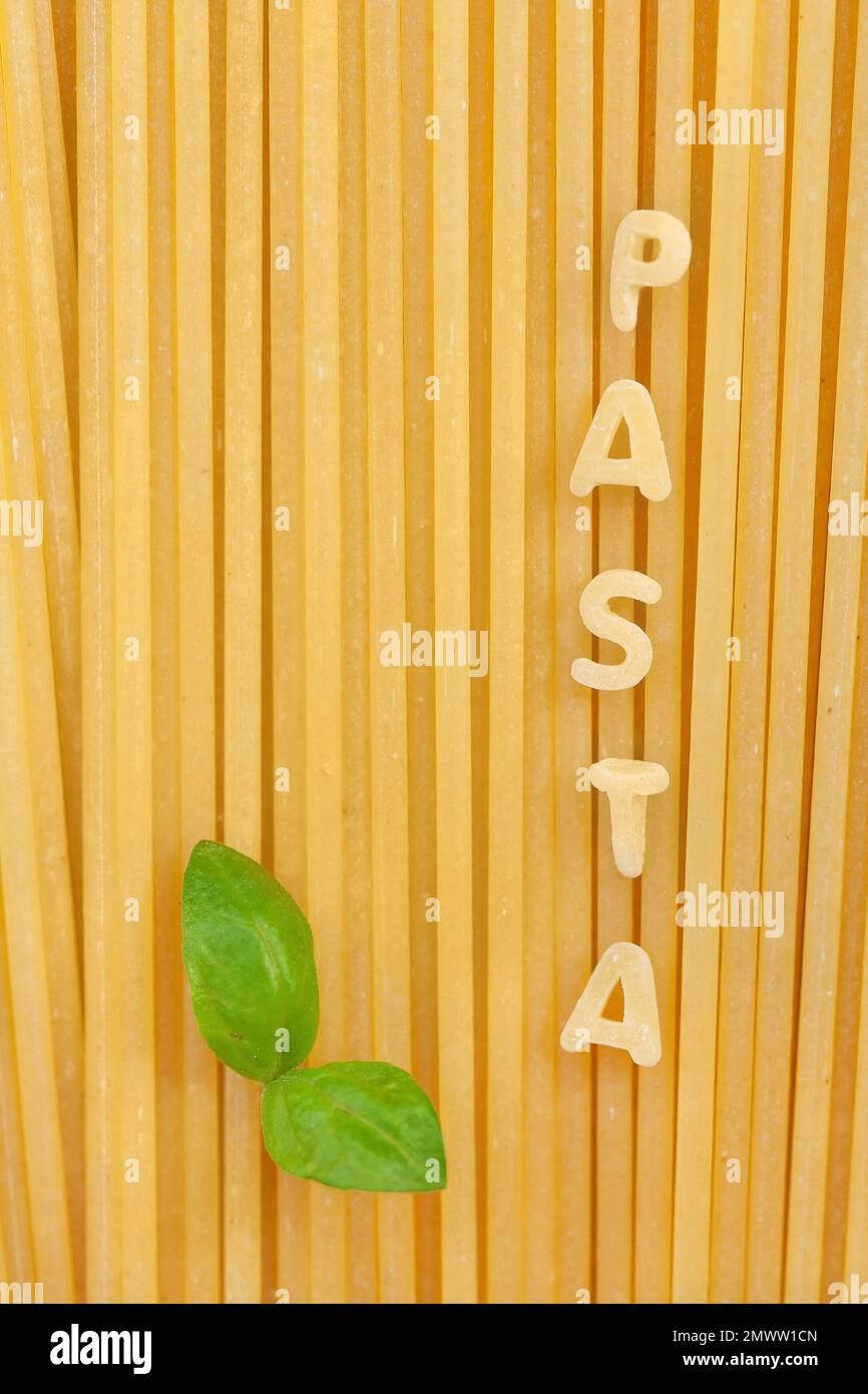 Pasta letters on spaghetti background with basil leaf Stock Photo - Alamy