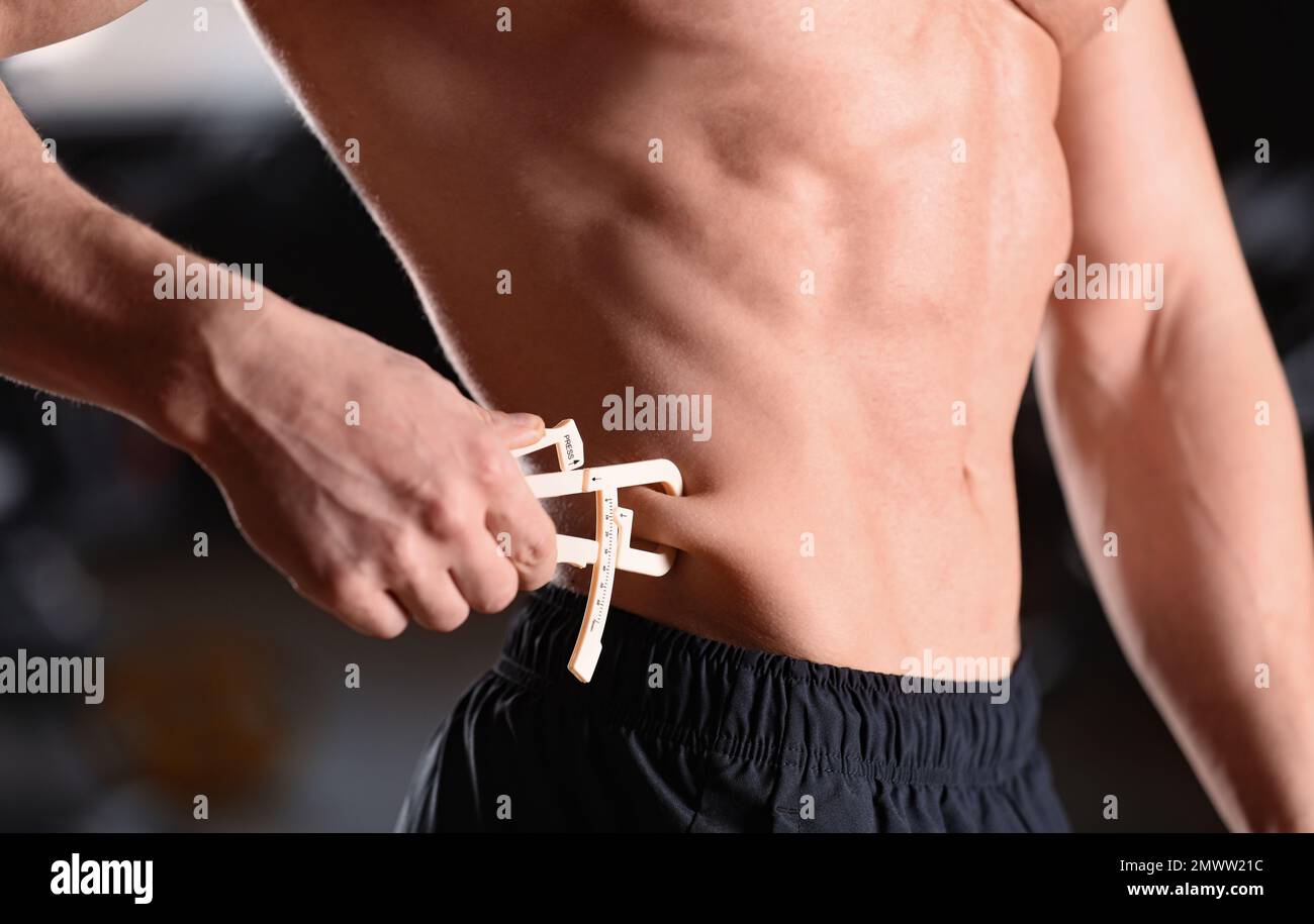 Man measuring body fat layer with caliper indoors, closeup Stock Photo ...