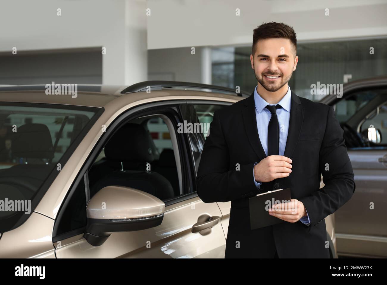Salesman with clipboard near car in dealership Stock Photo - Alamy