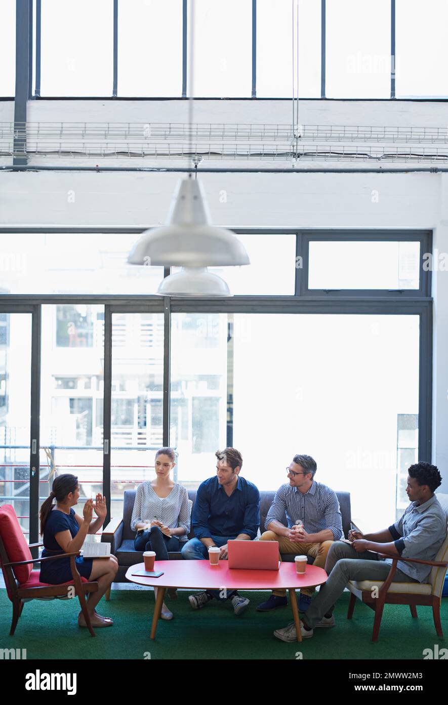 Explaining her vision. a group of office workers talking together in a ...