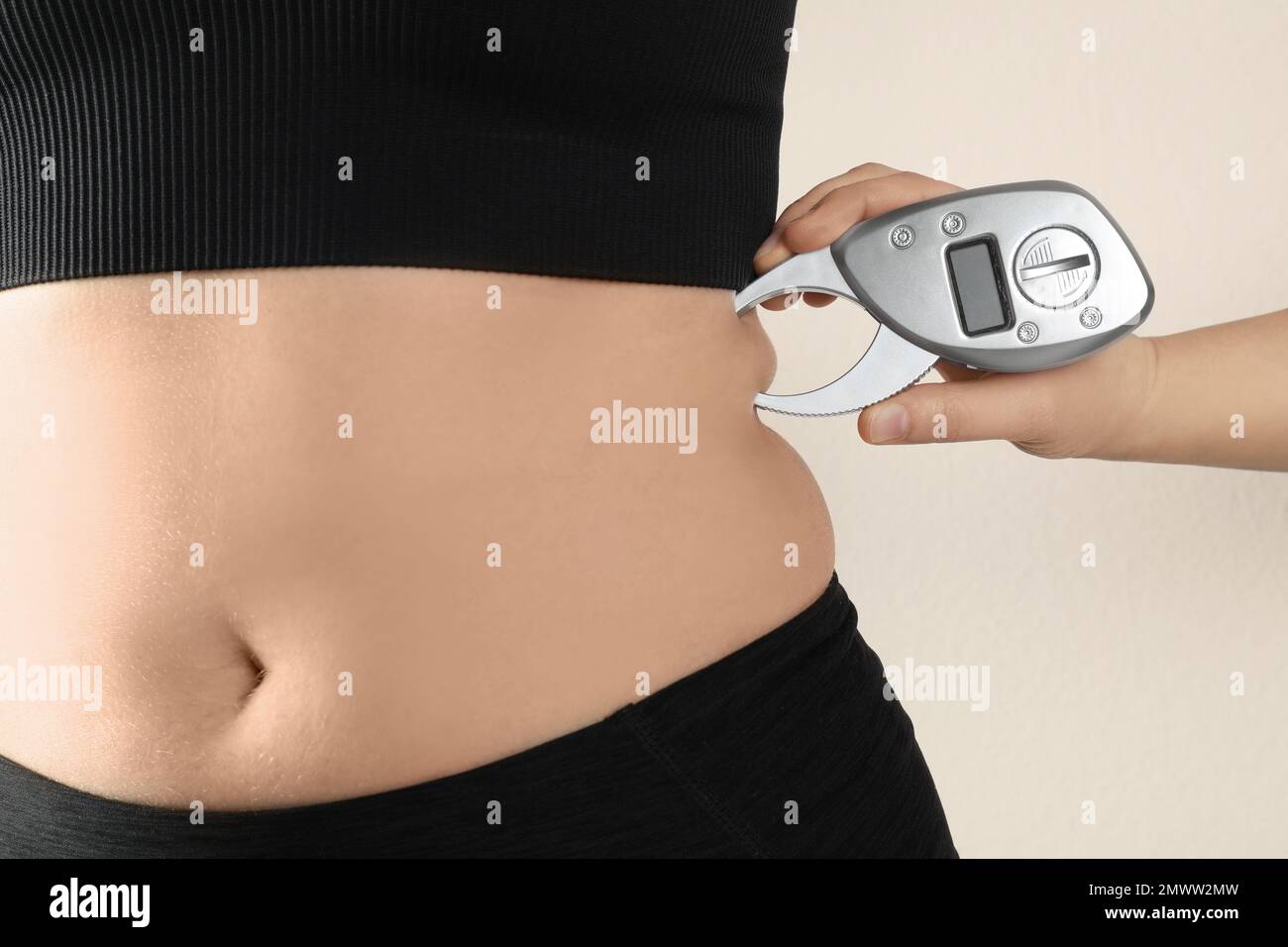 Nutritionist measuring woman's body fat layer with digital caliper on ...