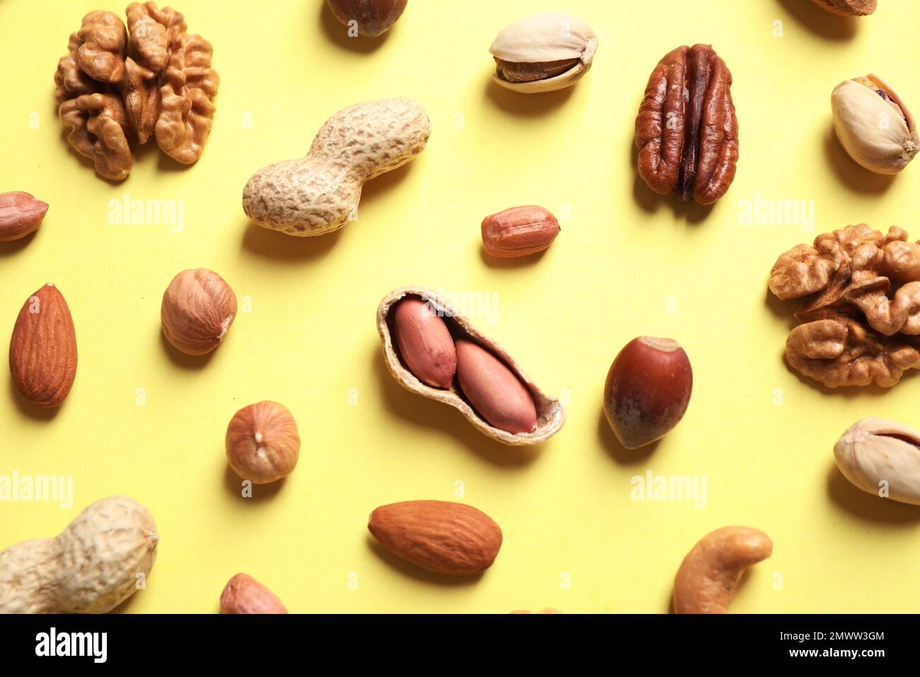 Different delicious nuts on yellow background, flat lay Stock Photo - Alamy