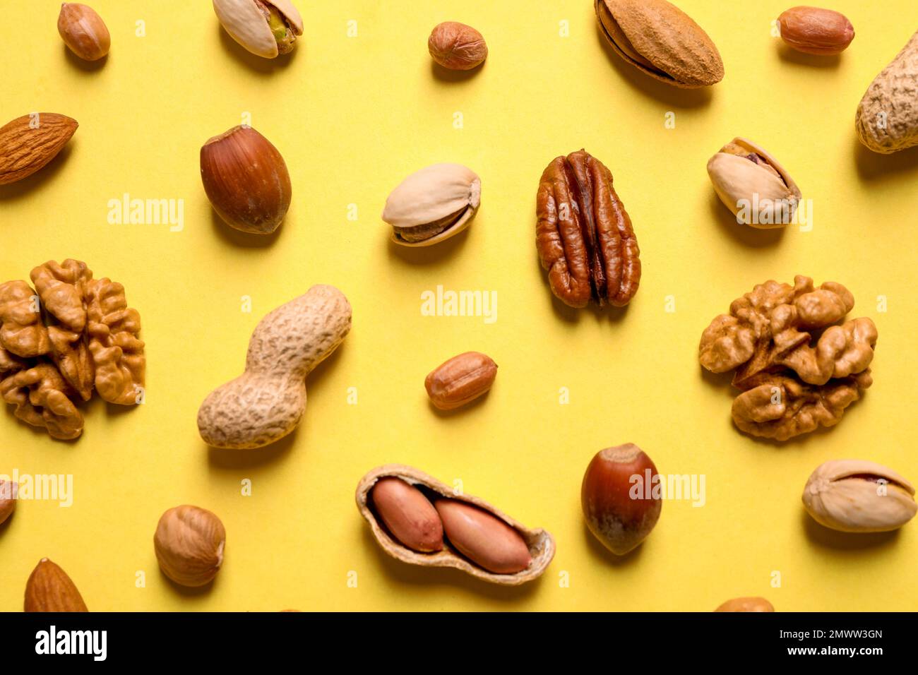 Different delicious nuts on yellow background, flat lay Stock Photo - Alamy