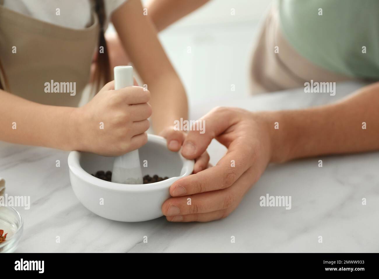 Father and daughter pounding pepper in kitchen, closeup. Cooking ...