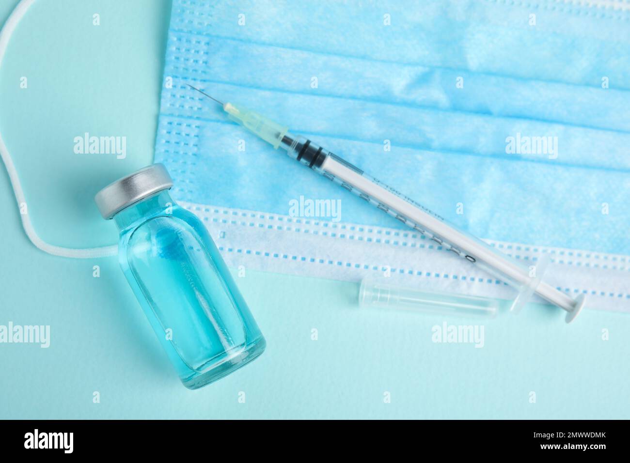 Vial, syringe and surgical mask on turquoise background, flat lay ...