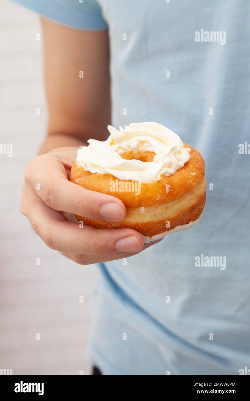 Hand of a male holding a tres leches brioche donut with whipped cream ...