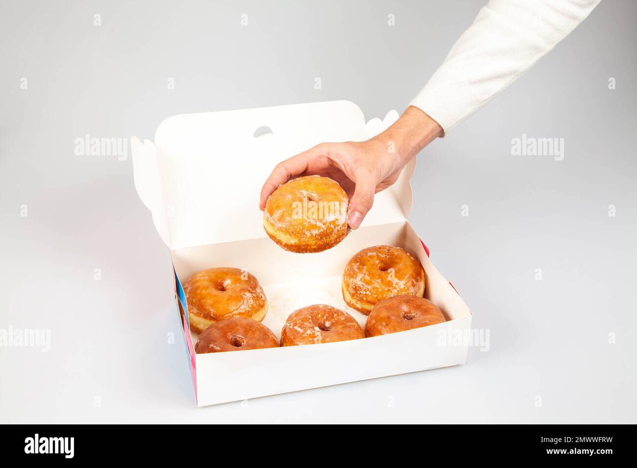 Donut packaging mock up template with hand holding a plain glazed donut ...