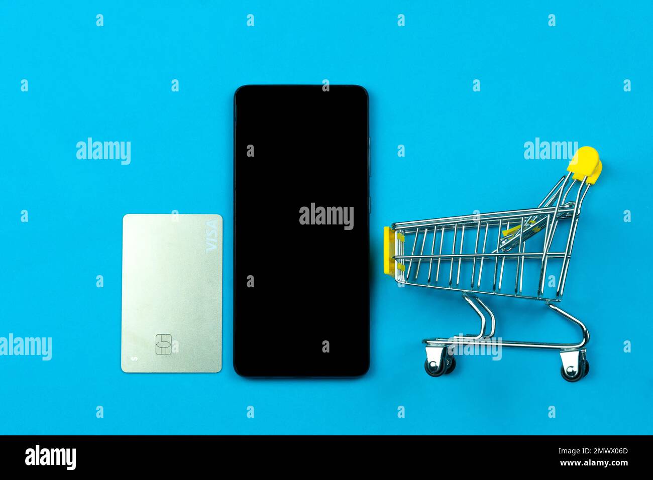 Card, mobile phone with black screen, shopping cart on blue background ...