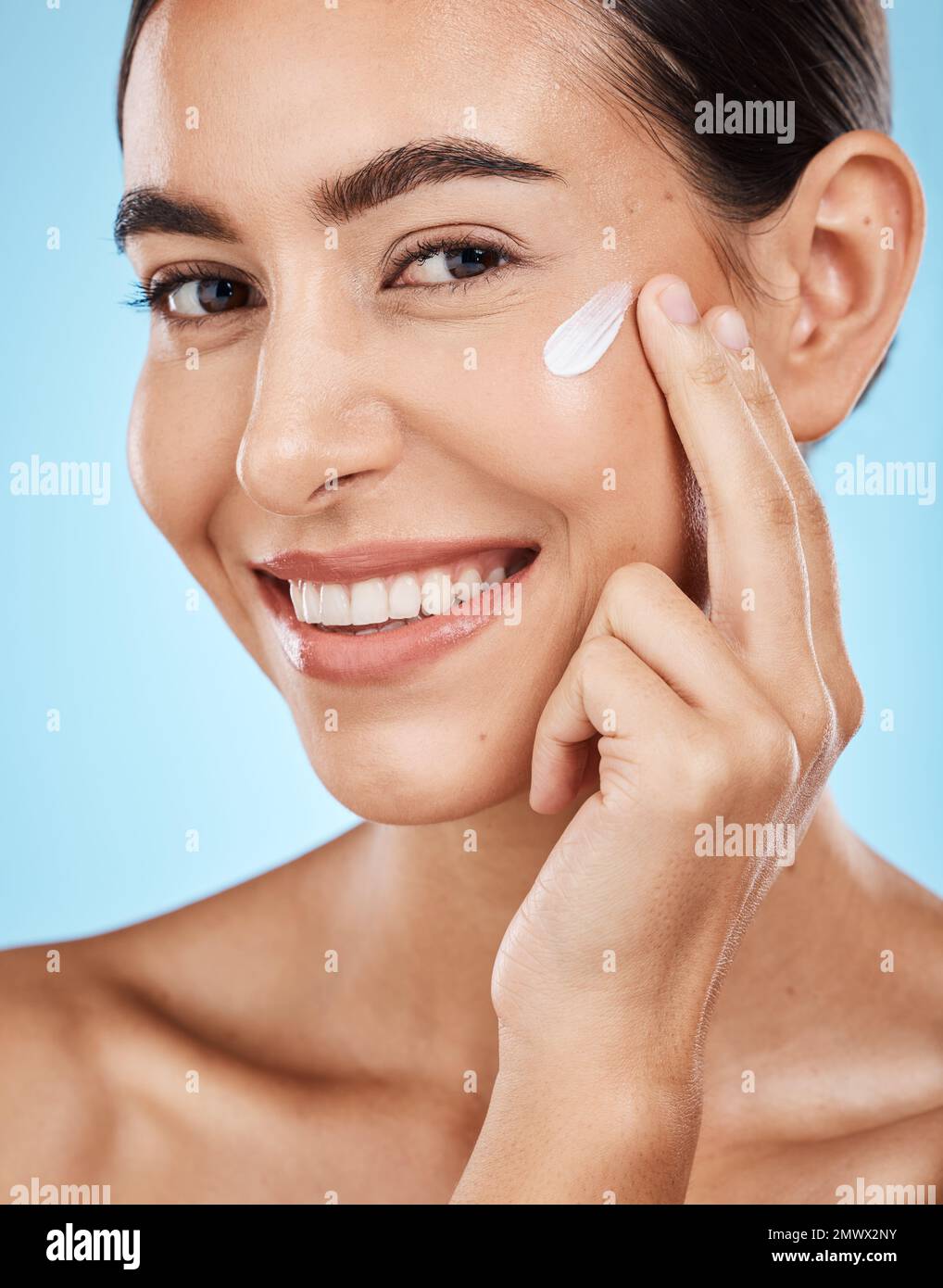 Portrait, cream and skincare with a model woman in studio on a blue ...