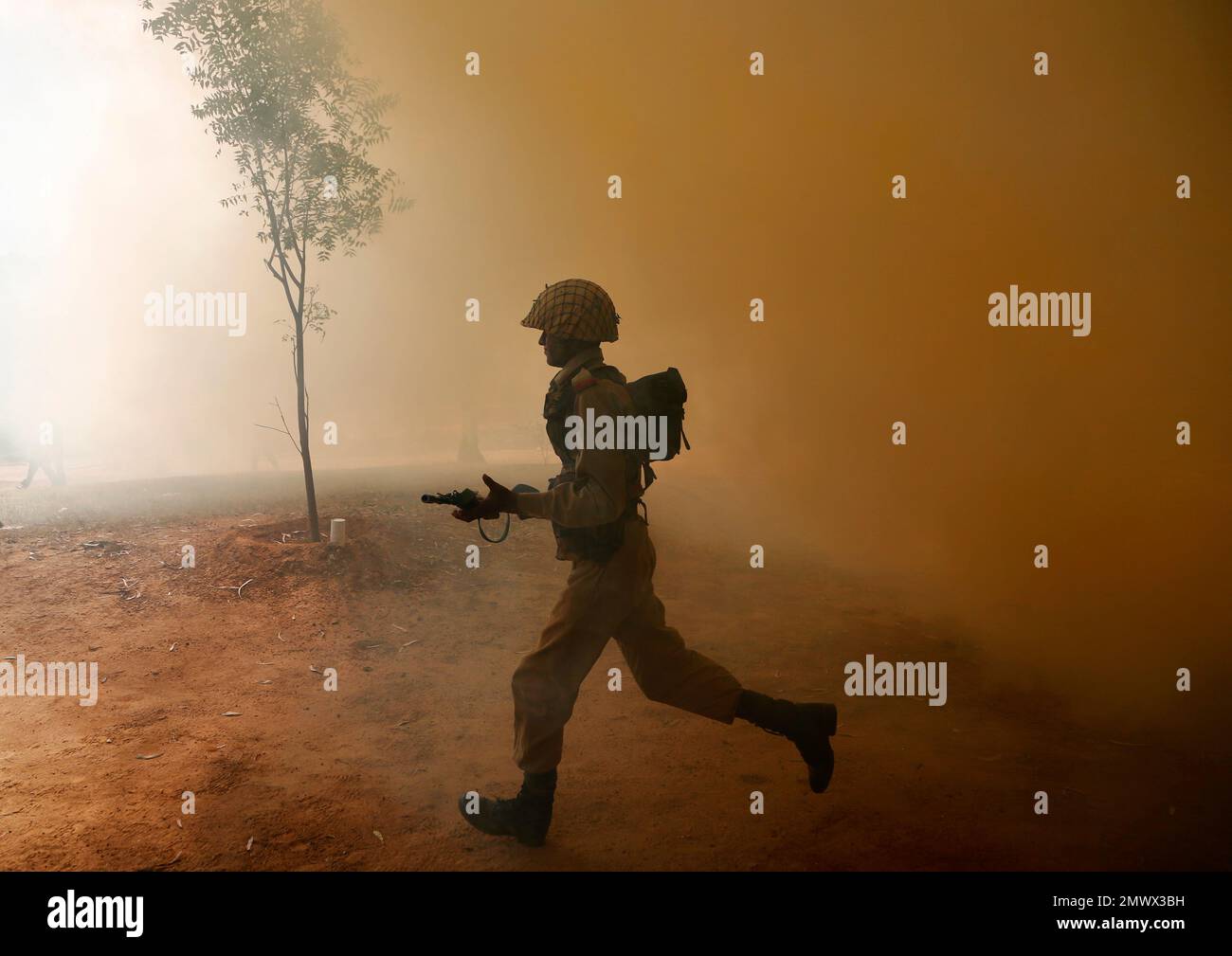 An Indian army soldier runs amid smoke from canisters during a session ...