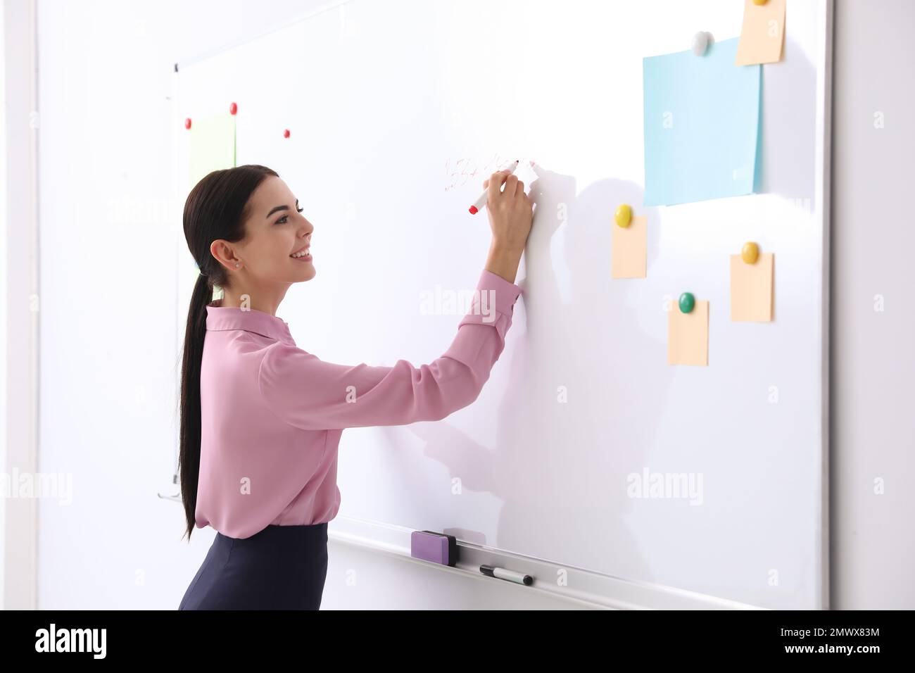 Young teacher writing on whiteboard in classroom Stock Photo - Alamy