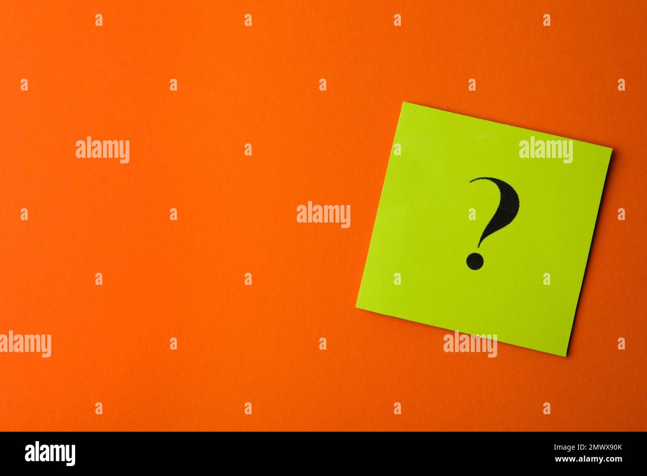 Green paper card with question mark on orange background, top view ...