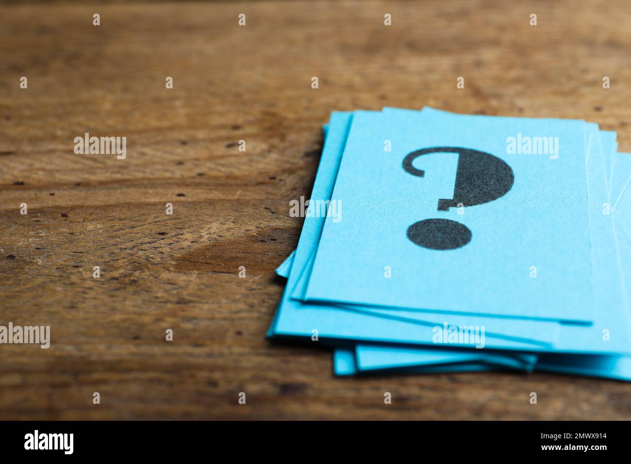 Blue paper cards with question mark on wooden background, closeup ...