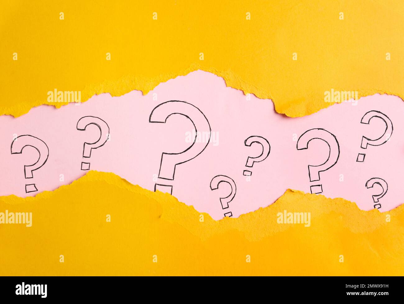 Question marks on pink background, view through hole in yellow paper ...