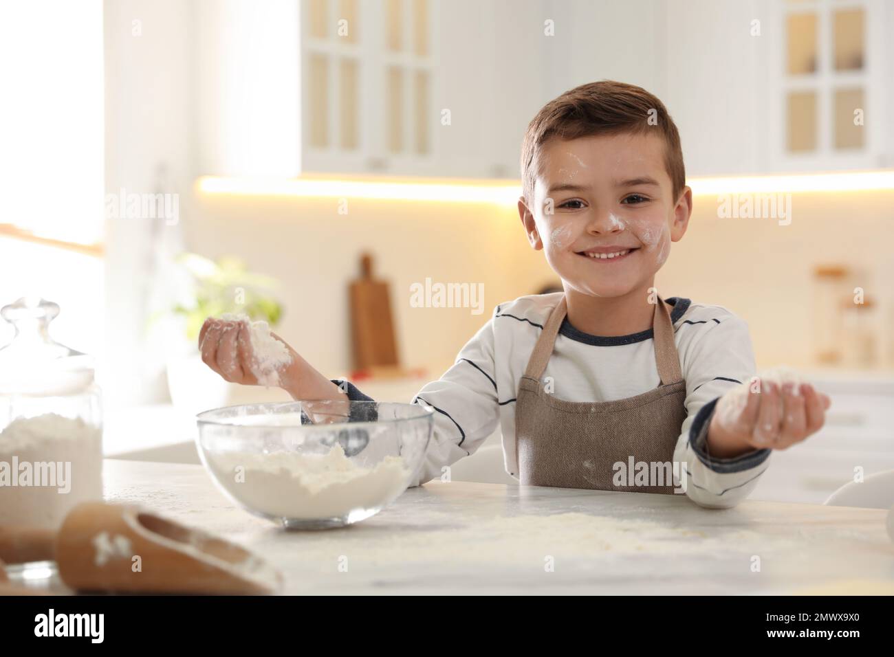 Cute little boy cooking dough at table in kitchen Stock Photo - Alamy