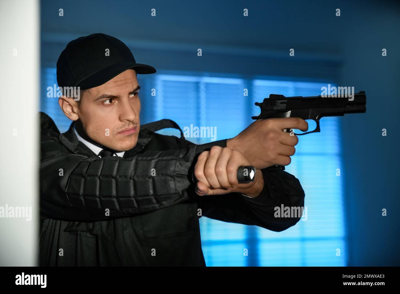 Professional security guard with flashlight and gun in dark room Stock ...