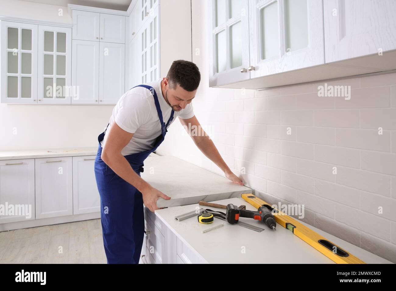 Worker installing new countertop in modern kitchen Stock Photo - Alamy