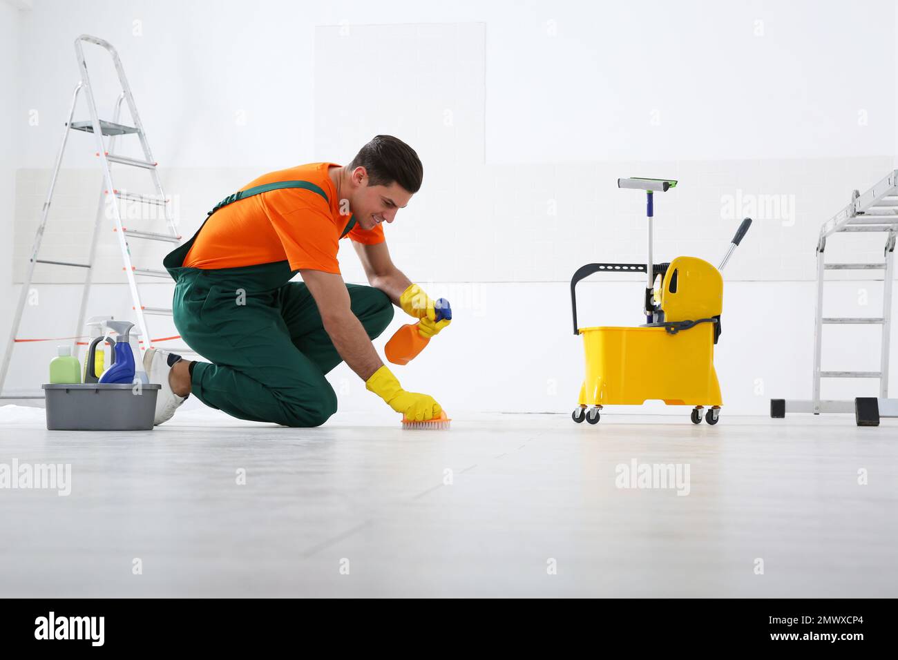 Professional janitor cleaning floor with brush and detergent after ...