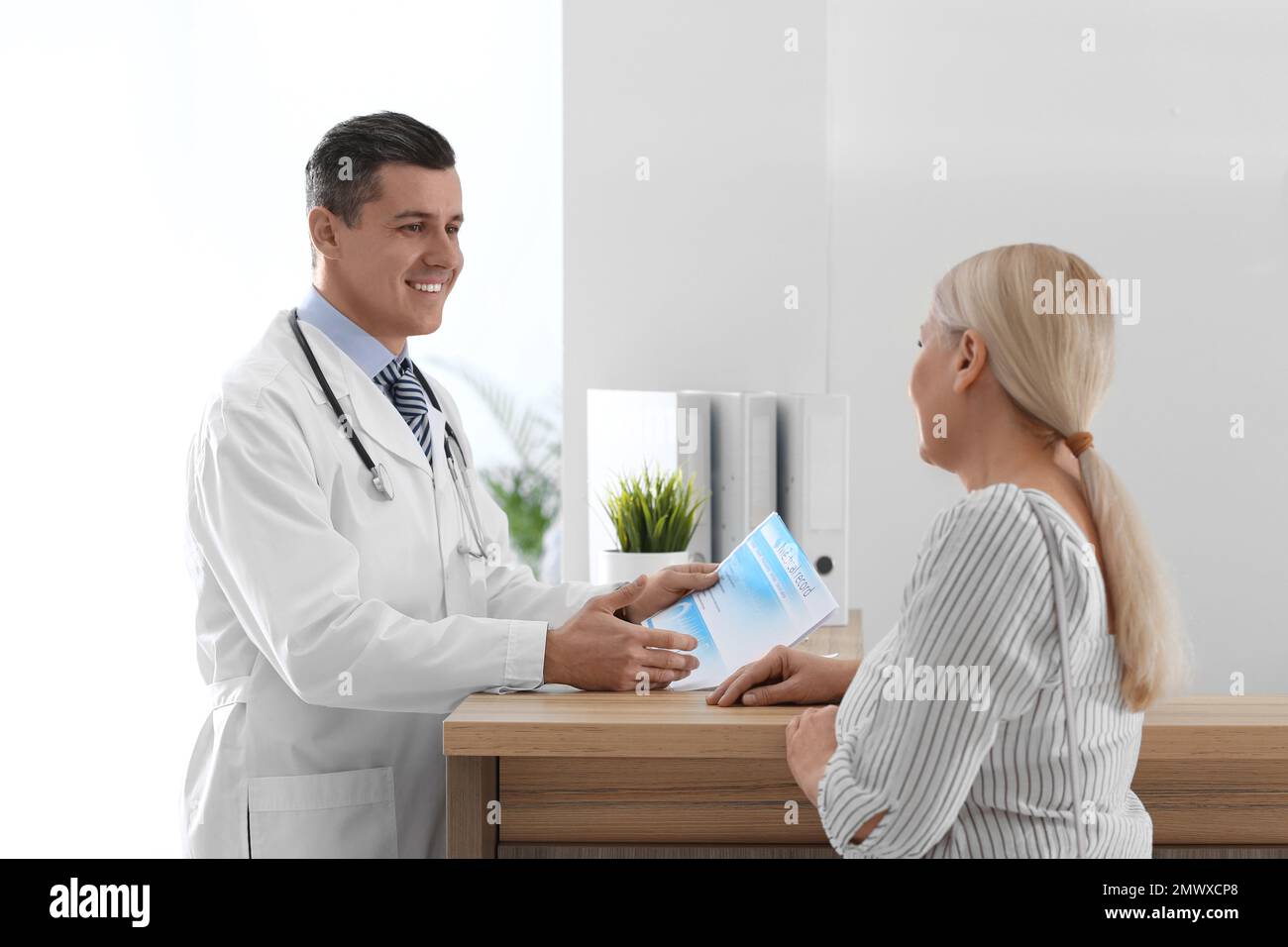 Doctor talking with patient near reception in hospital Stock Photo - Alamy